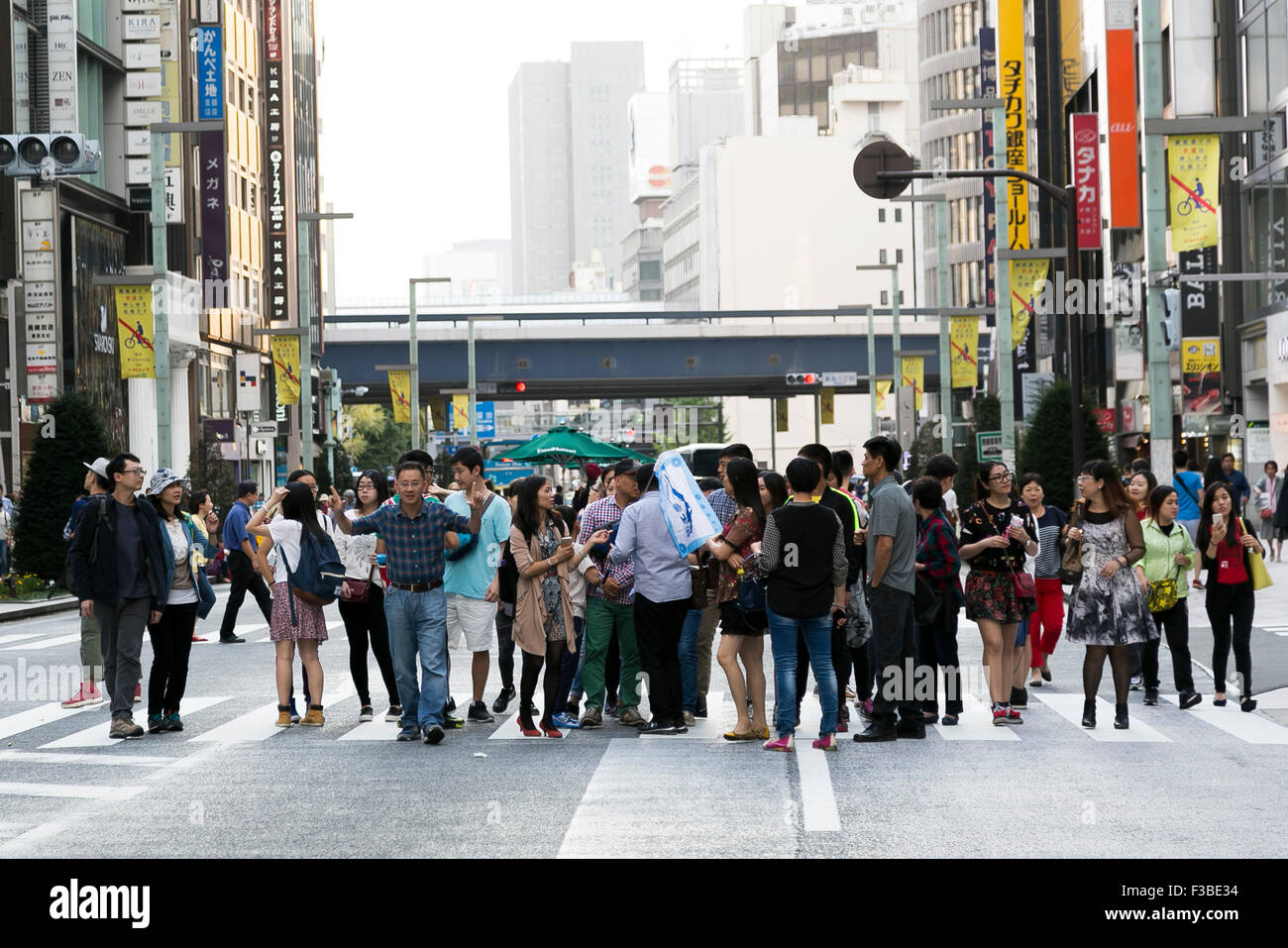 Chinese tourists walk past luxury shops in Ginza shopping district ...