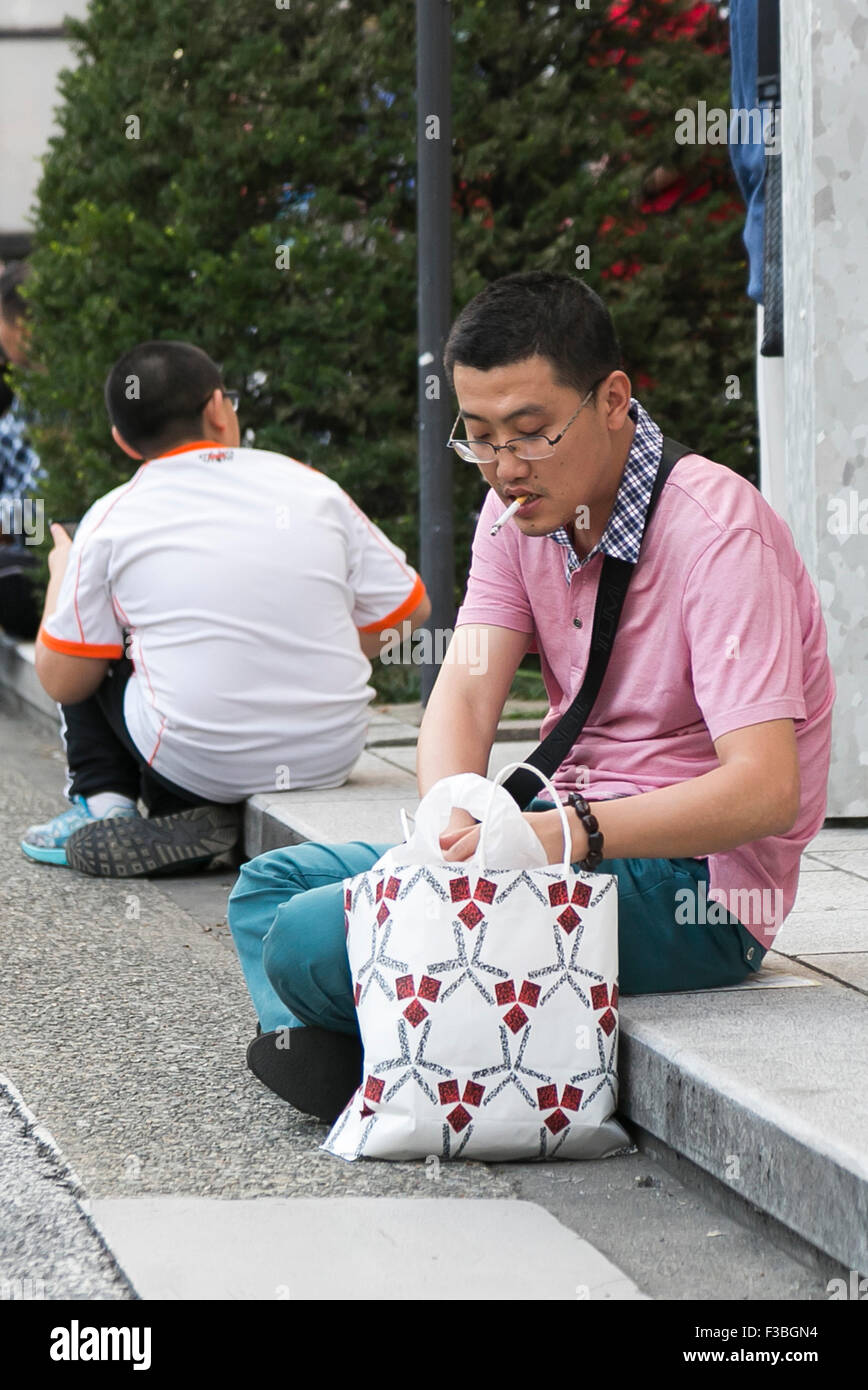 A Chinese tourist smokes on the main street of Ginza shopping district ...