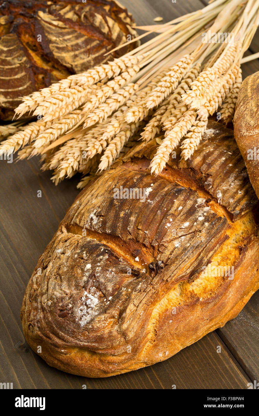 Home-made bread loaves of different flavours with wheat ears on wooden ...