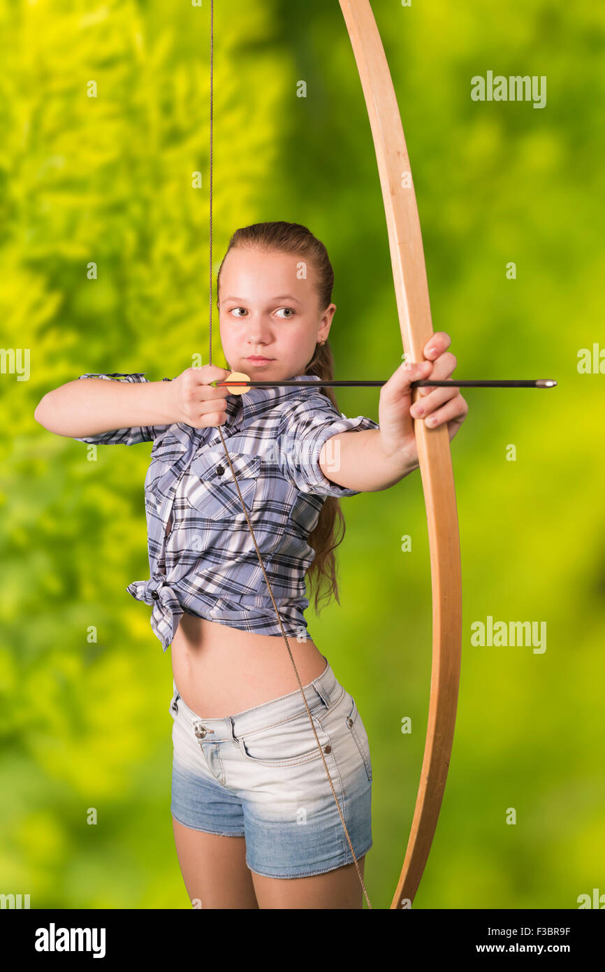 Teen girl practicing archery on green natural background Stock Photo ...