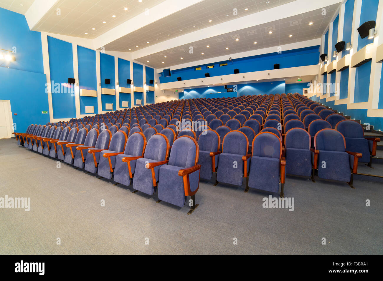 View on rows of comfortable blue chairs in illuminate blue room cinema ...