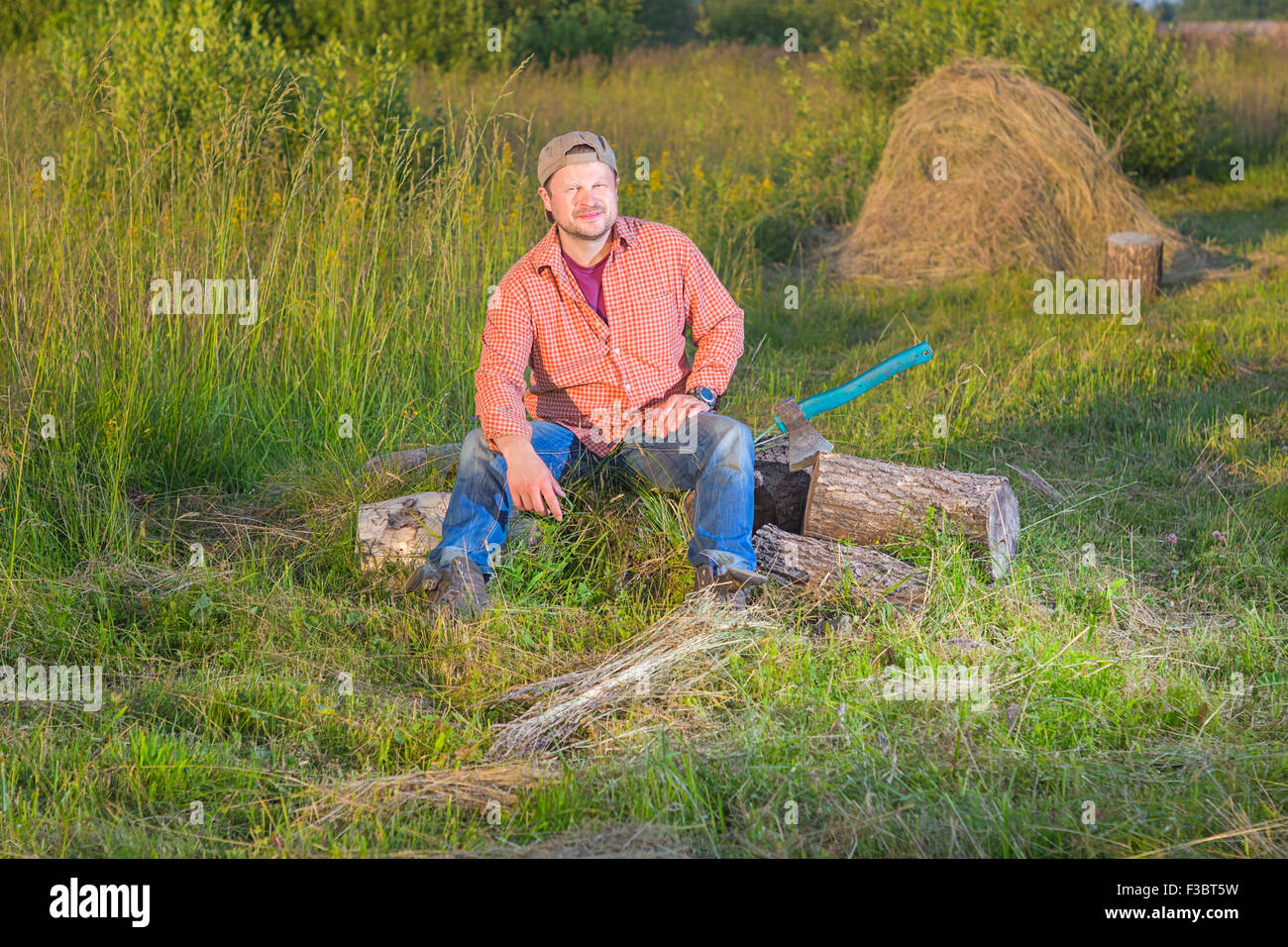 Farmer with an axe sitting near haystack Stock Photo - Alamy