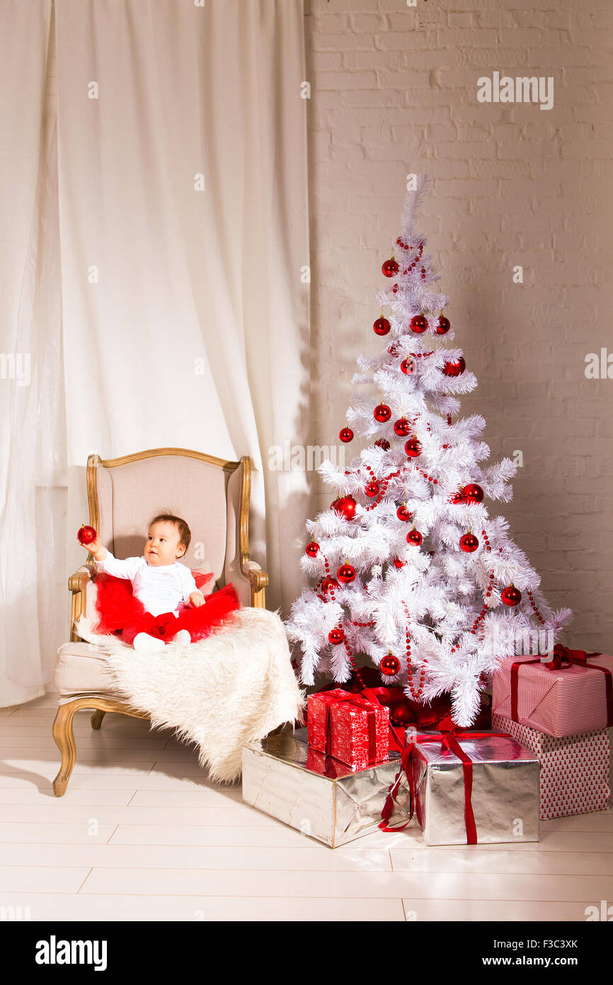 girl sitting in a chair. Christmas tree Stock Photo - Alamy