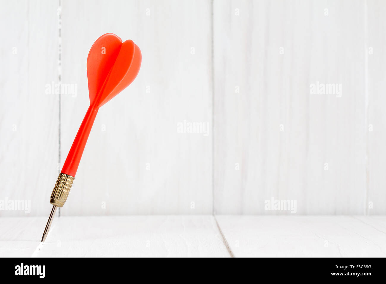 Red dart on a white wooden background Stock Photo - Alamy