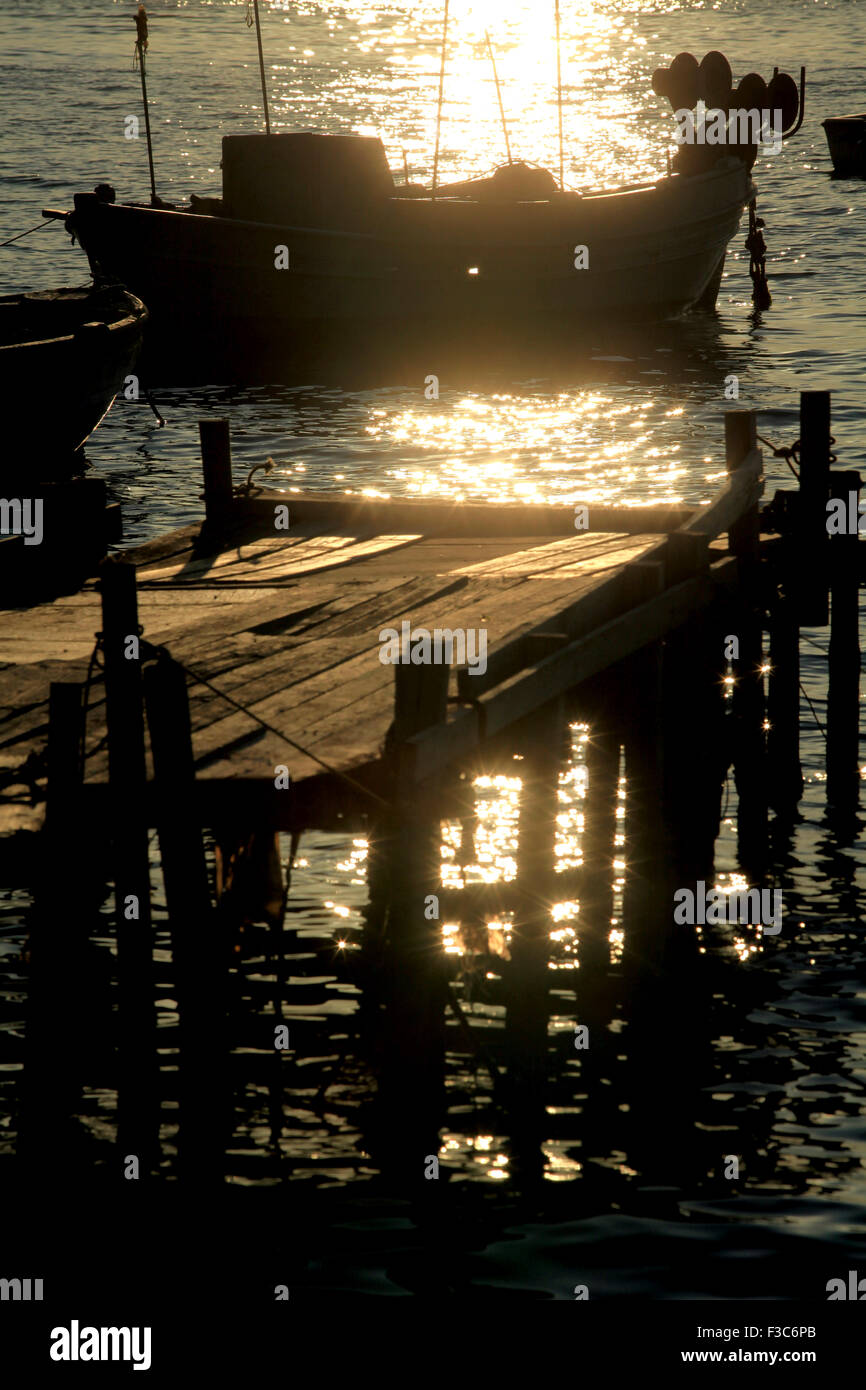 Wooden pier with boats at sunset Stock Photo - Alamy