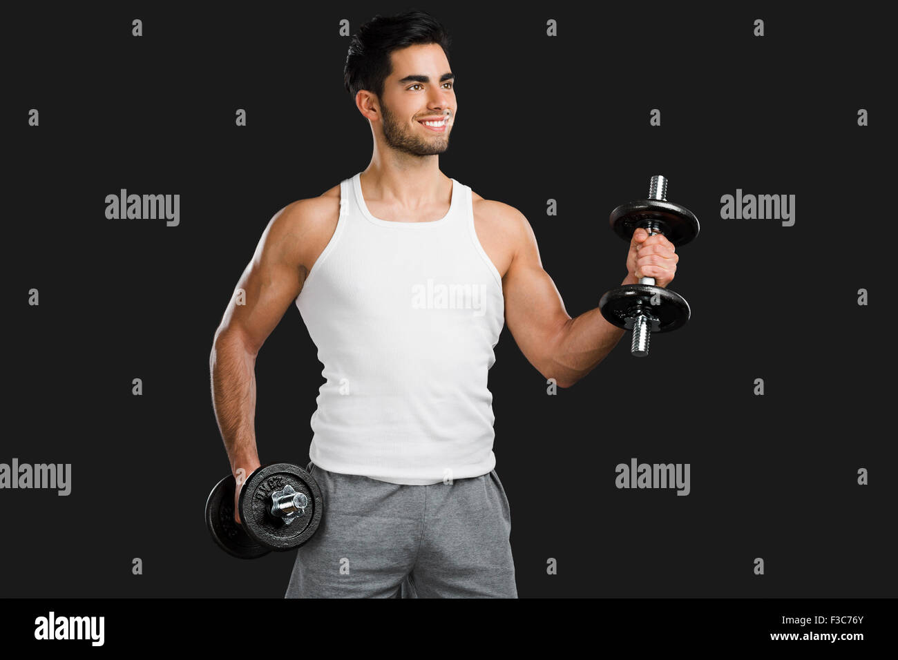Portrait of handsome young man lifting weights, isolated over a gray ...