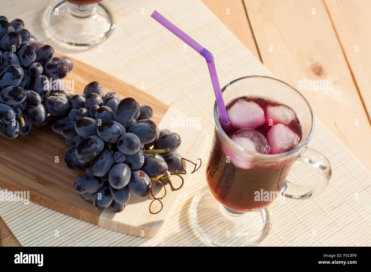 Grape juice cooler with ice in glass and glass of fresh blue grapes on ...