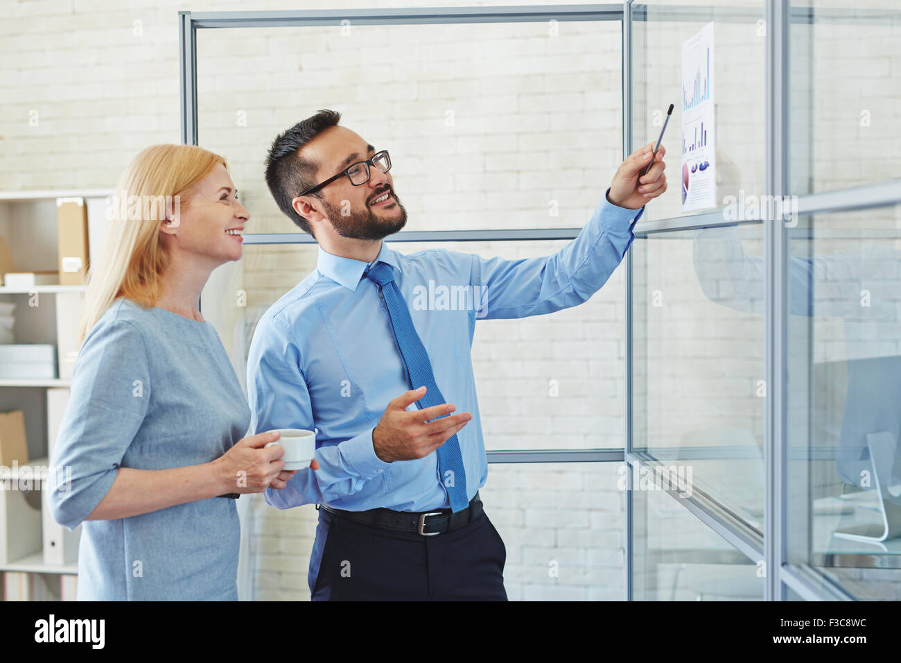 Two office workers discussing paper with financial data Stock Photo - Alamy