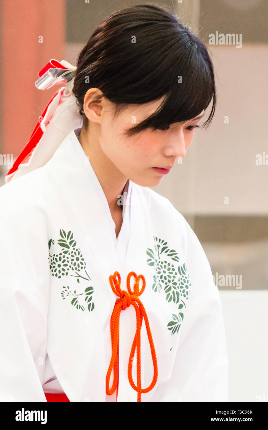 At the Ikuta Shinto Shrine in Kobe, a young Miko, shrine maiden, bows ...