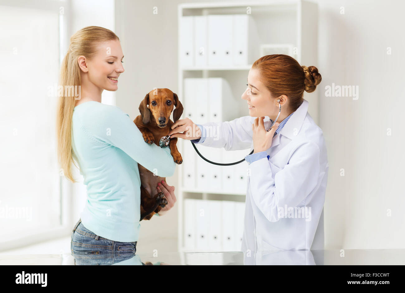 happy woman with dog and doctor at vet clinic Stock Photo - Alamy