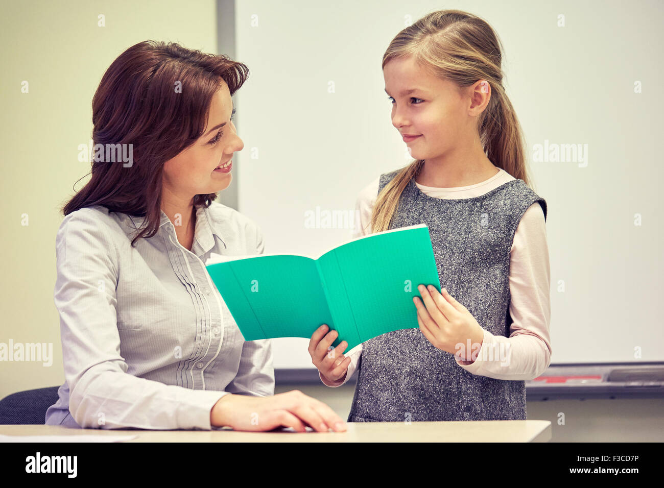 school girl with notebook and teacher in classroom Stock Photo - Alamy