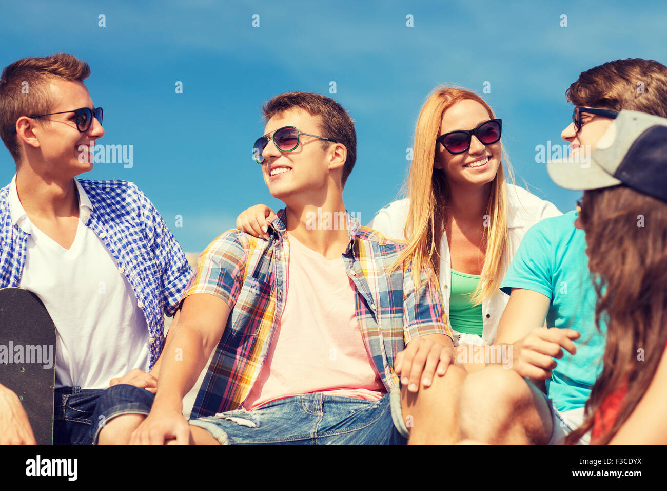group of smiling friends sitting on city street Stock Photo - Alamy