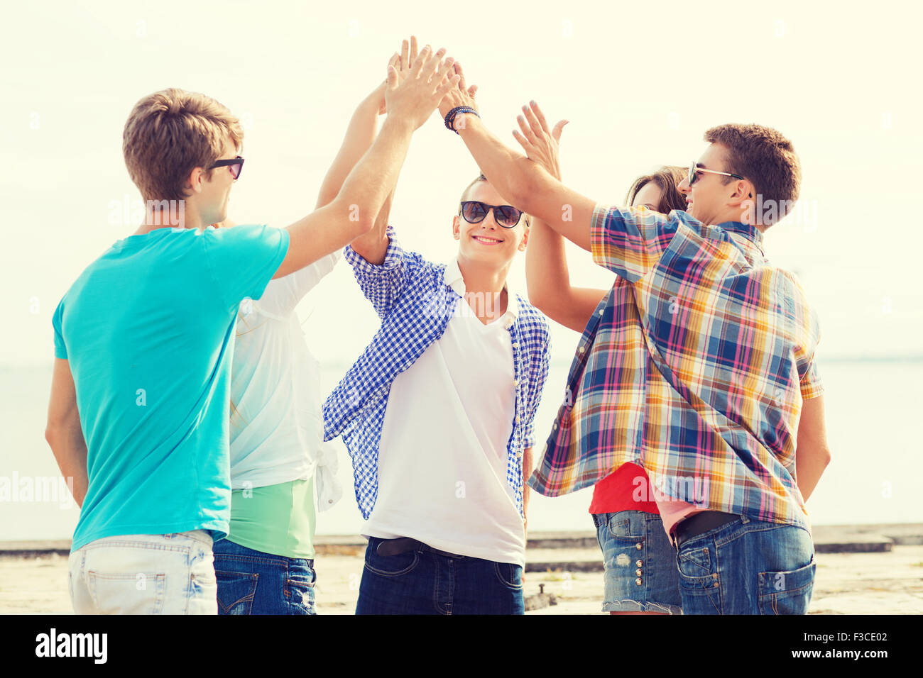 group of smiling friends making high five outdoors Stock Photo - Alamy
