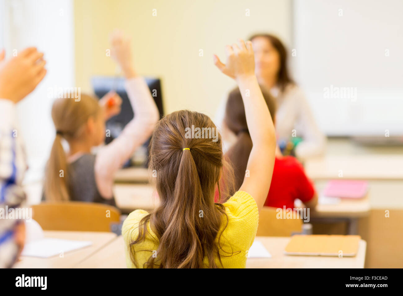 group of school kids raising hands in classroom Stock Photo - Alamy