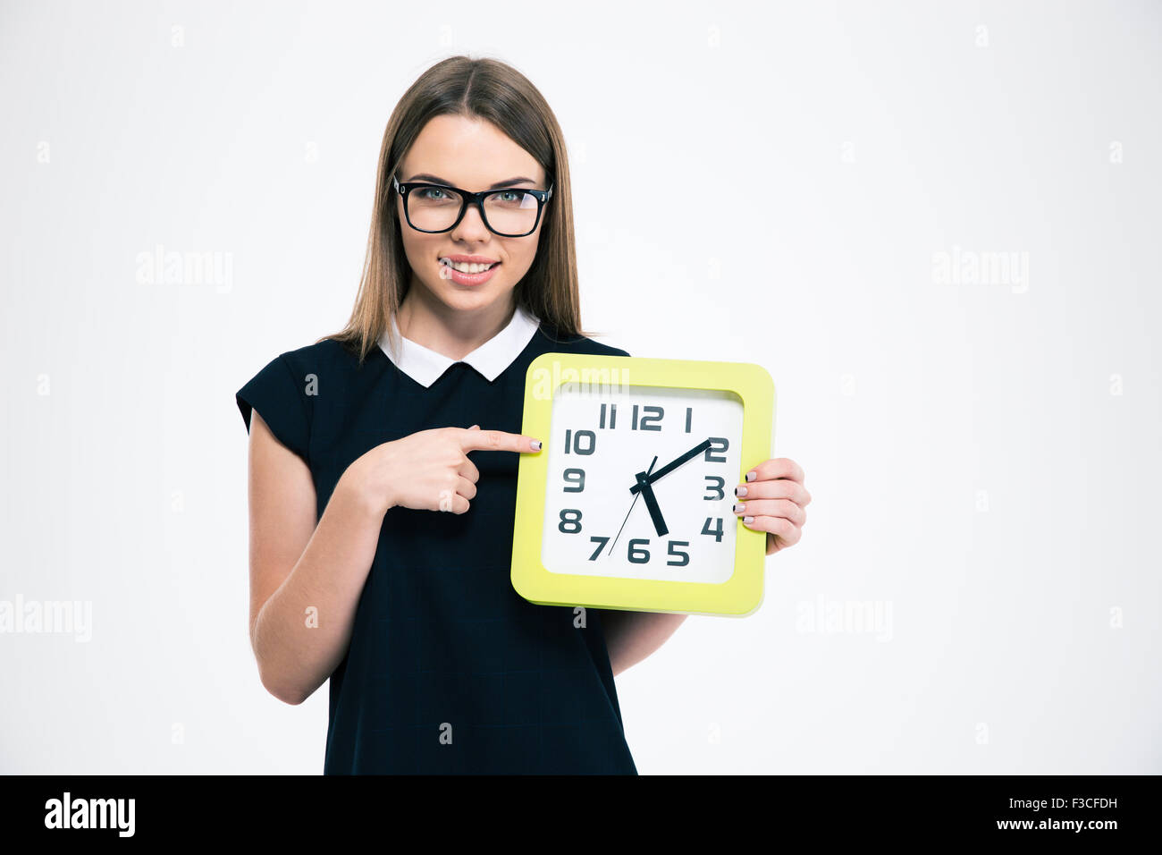 Portrait of a happy young woman pointing finger on big clock isolated ...