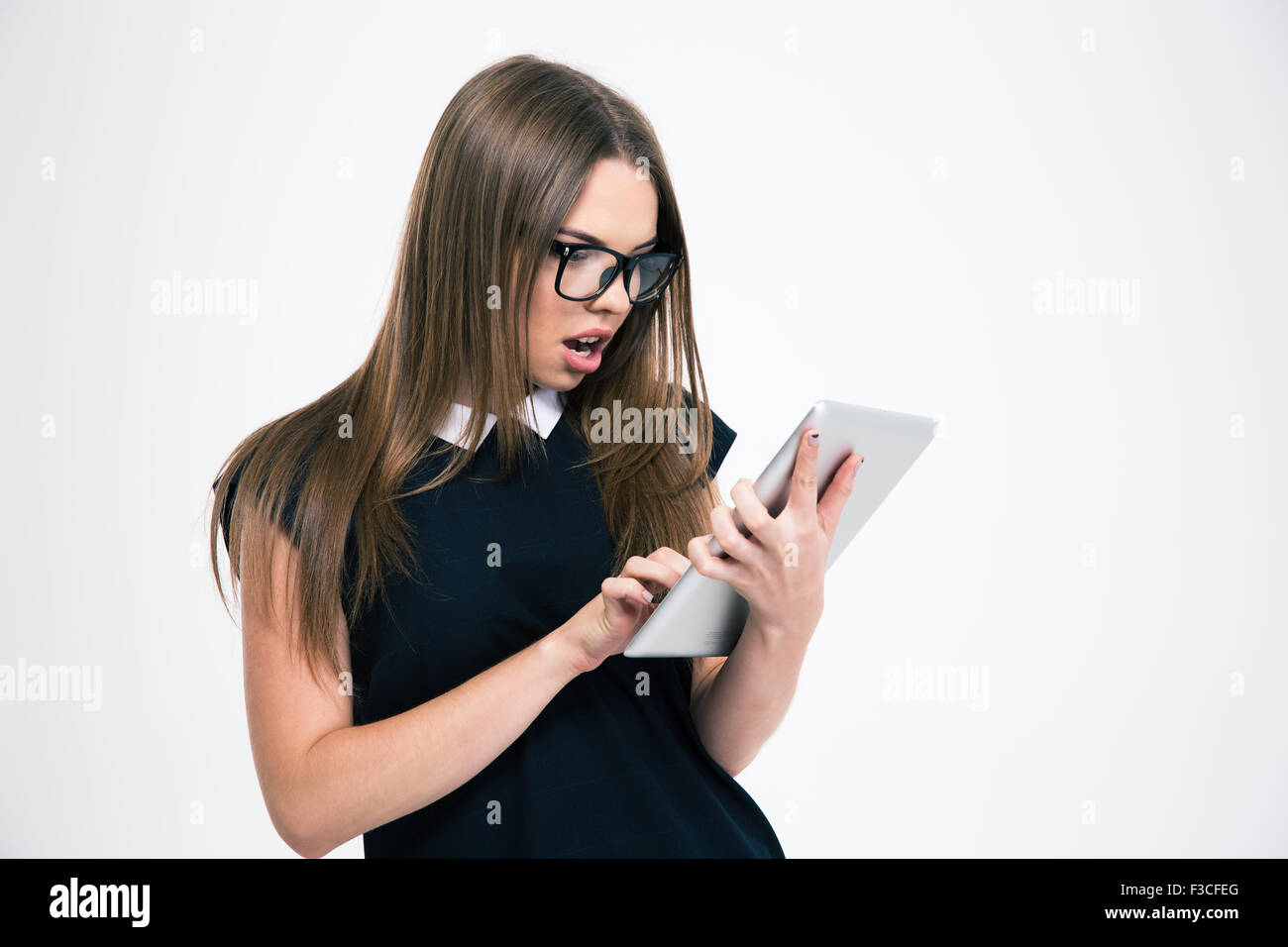 Portrait of a shocked young woman using tablet computer isolated on a ...