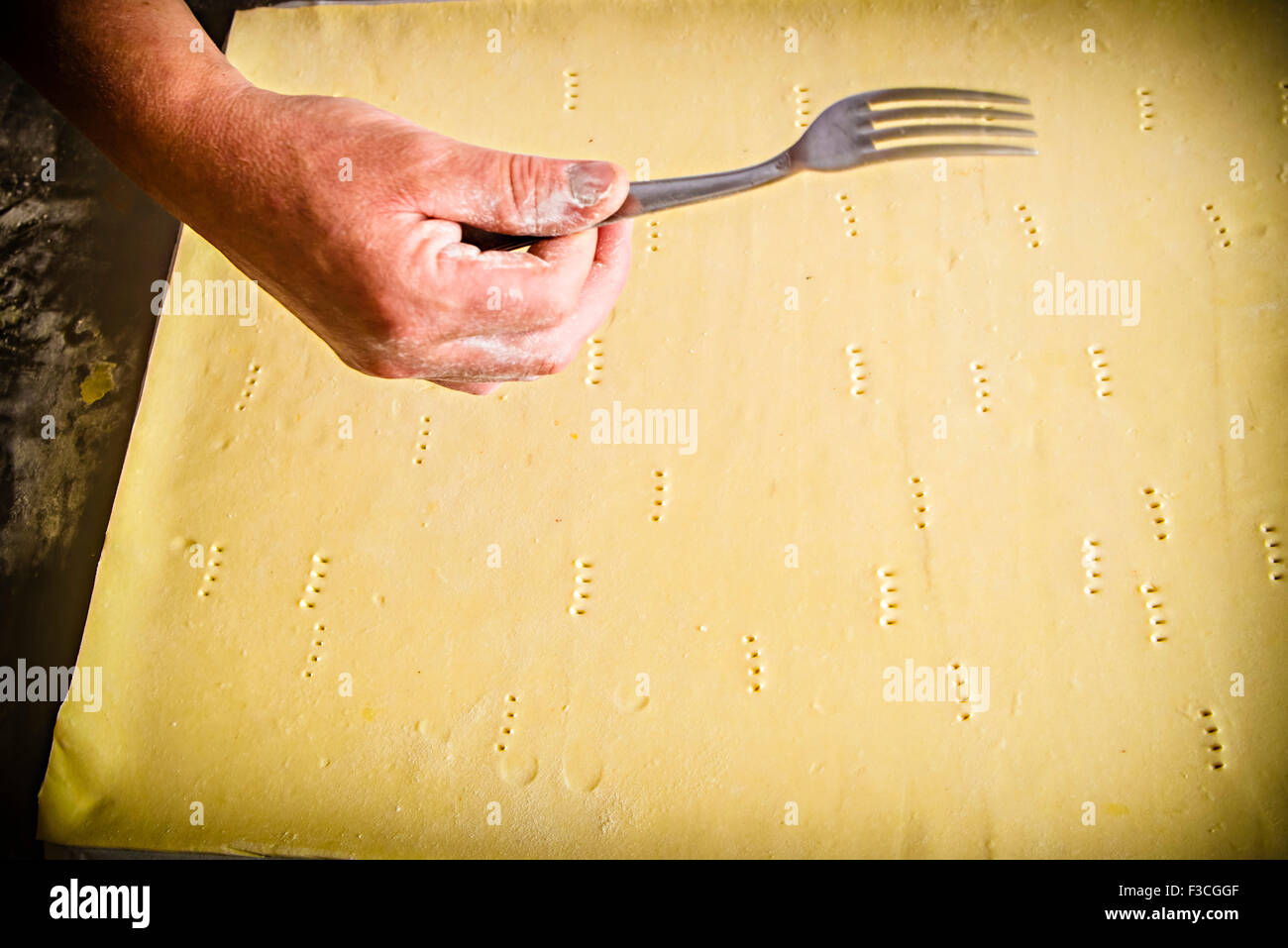 Person using a fork to poke holes in fresh dough Stock Photo - Alamy