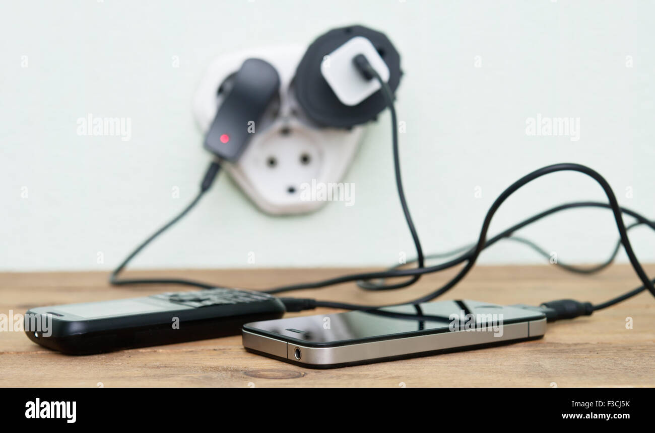 Smart phone and mobile phone charging with cable on the wooden table ...