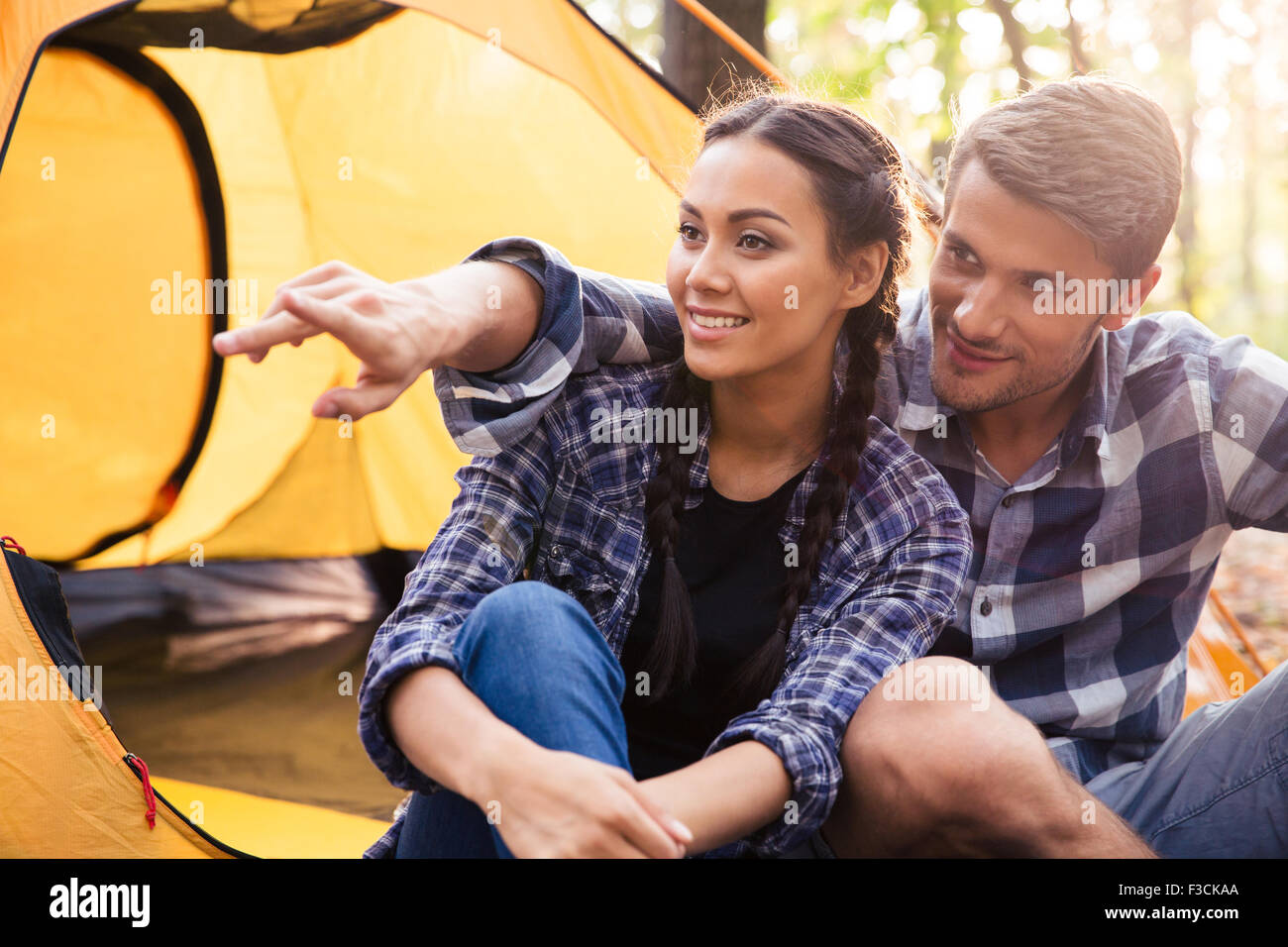 Portrait of a man pointing on something to his girlfriend in the forest ...