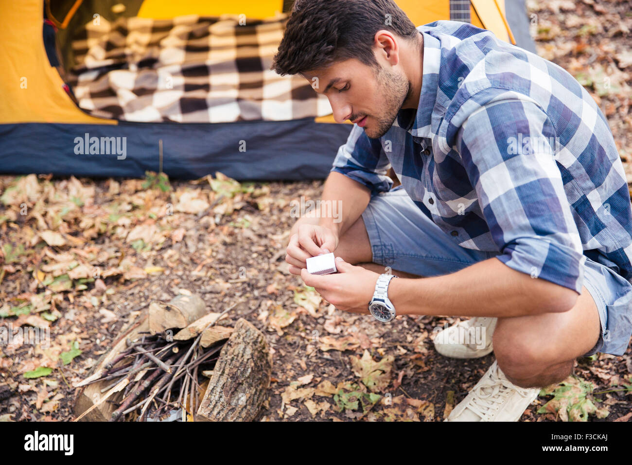 Portrait of a young man kindle bonfire in the forest Stock Photo - Alamy