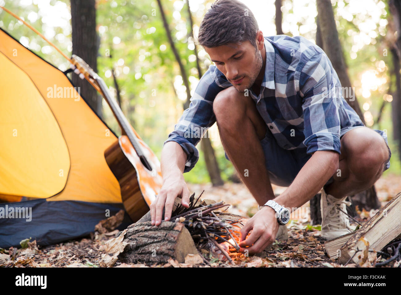 Portrait of a handsome man kindle bonfire in the forest Stock Photo - Alamy