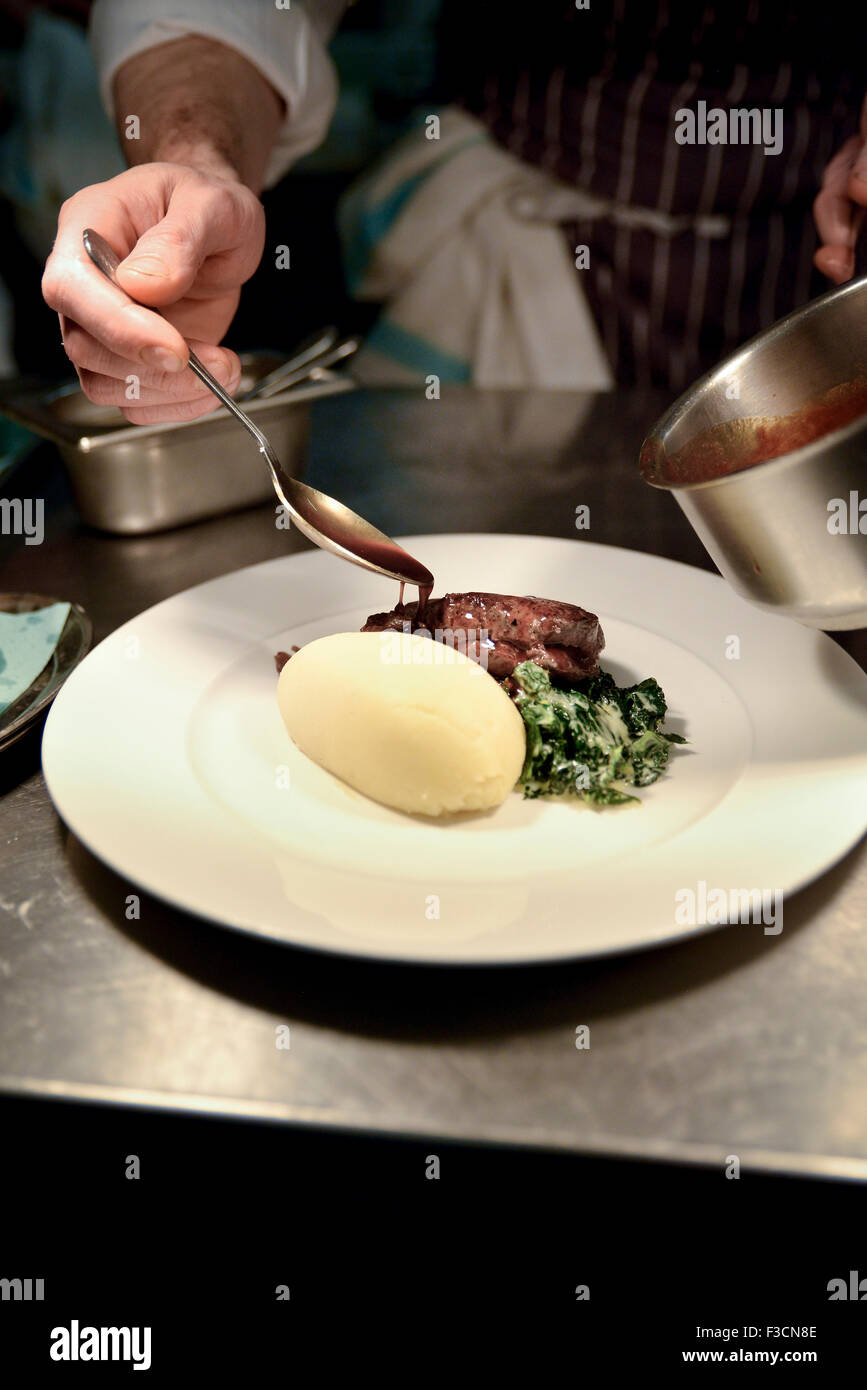 Restaurant chef pouring sauce on meat and potato dish Stock Photo - Alamy