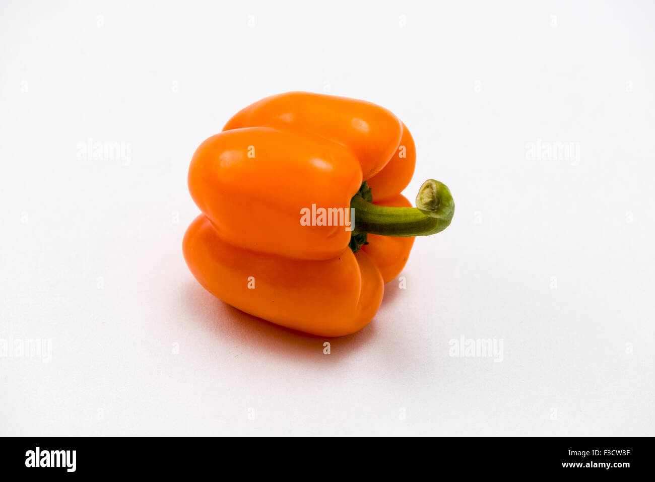 An orange capsicum (Capsicum annuum), displayed on a white table Stock ...