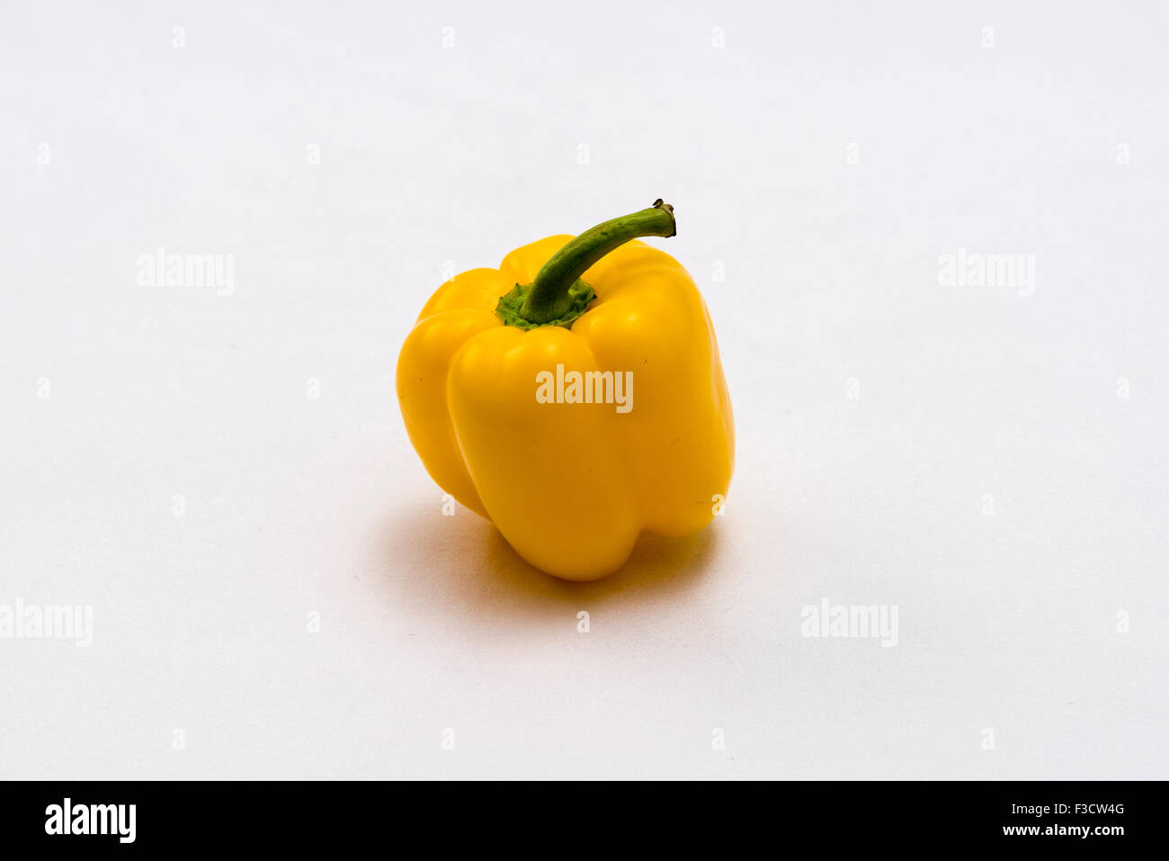 A yellow capsicum (Capsicum annuum), displayed on white table Stock ...