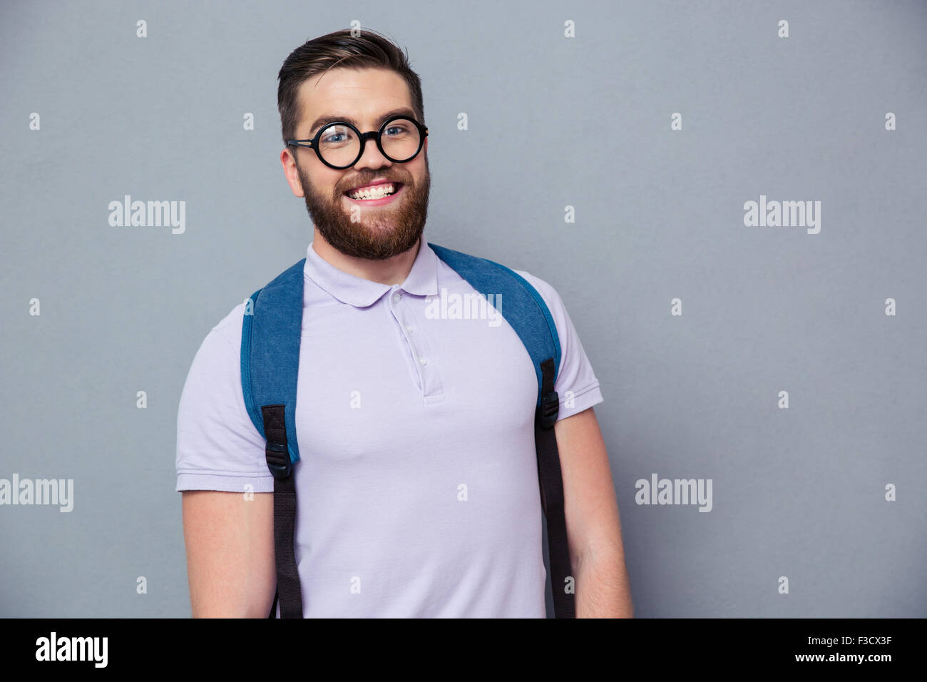 Portrait of a cheerful male nerd looking at camera over gray background ...