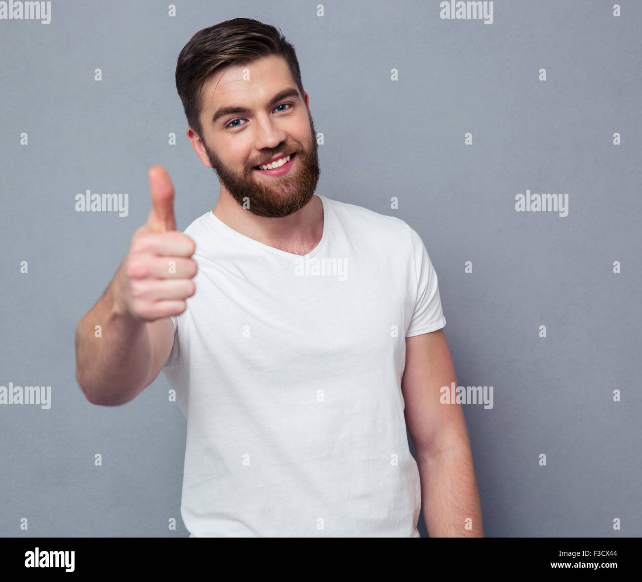 Portrait of a smiling casual man showing thumb up and loking at camera ...