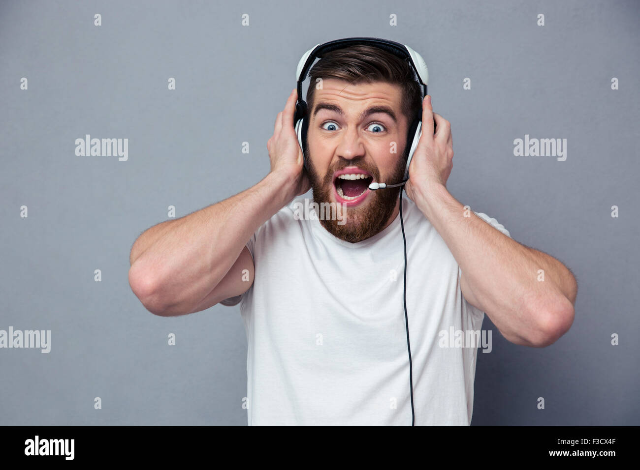 Portrait of a man in headphones screaming over gray background Stock ...
