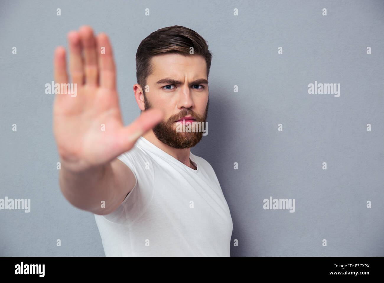 Portrait of a casual man showing stop sign over gray background Stock ...