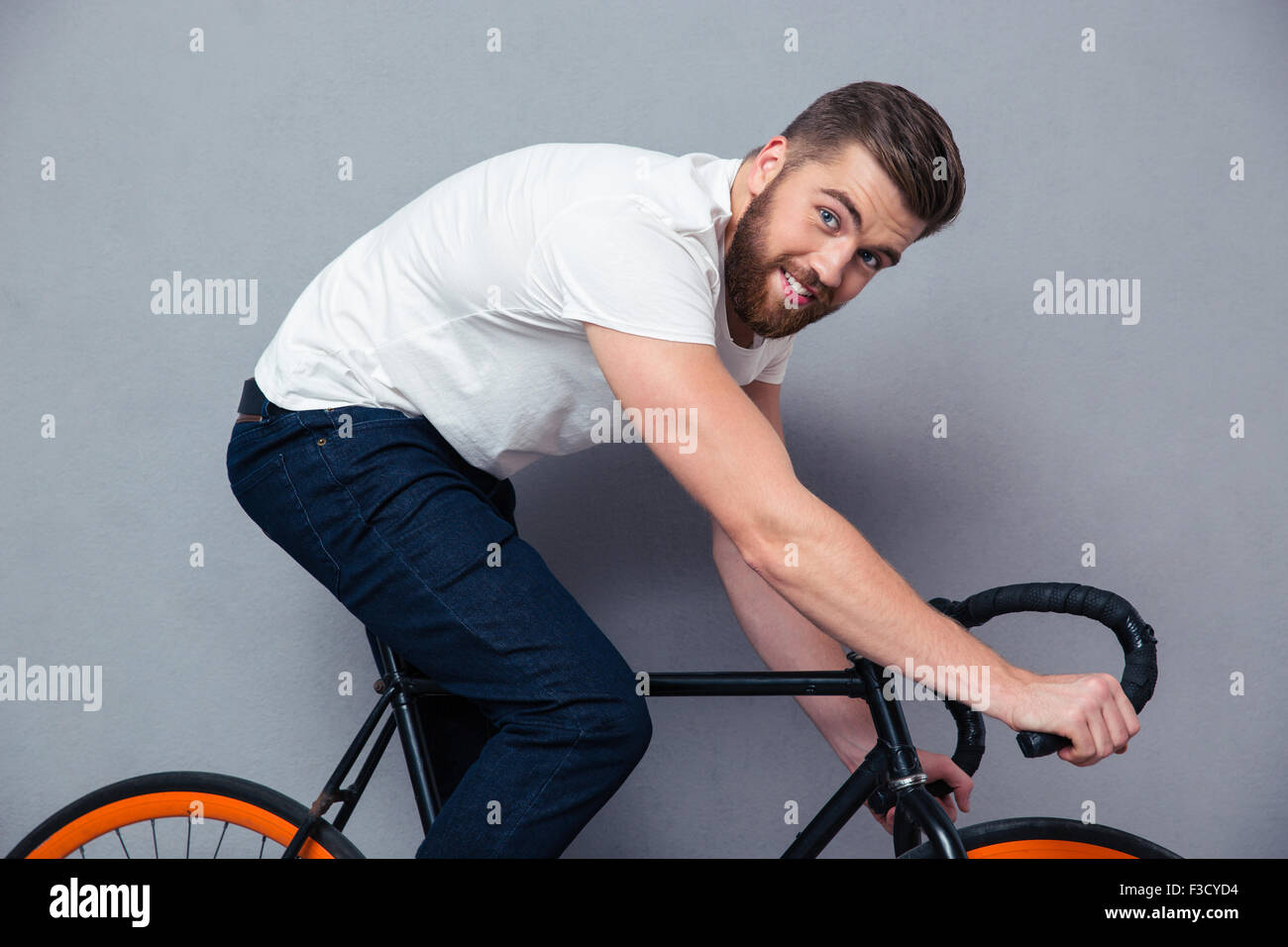 Portrait of a smiling man riding on bicycle over gray background Stock ...