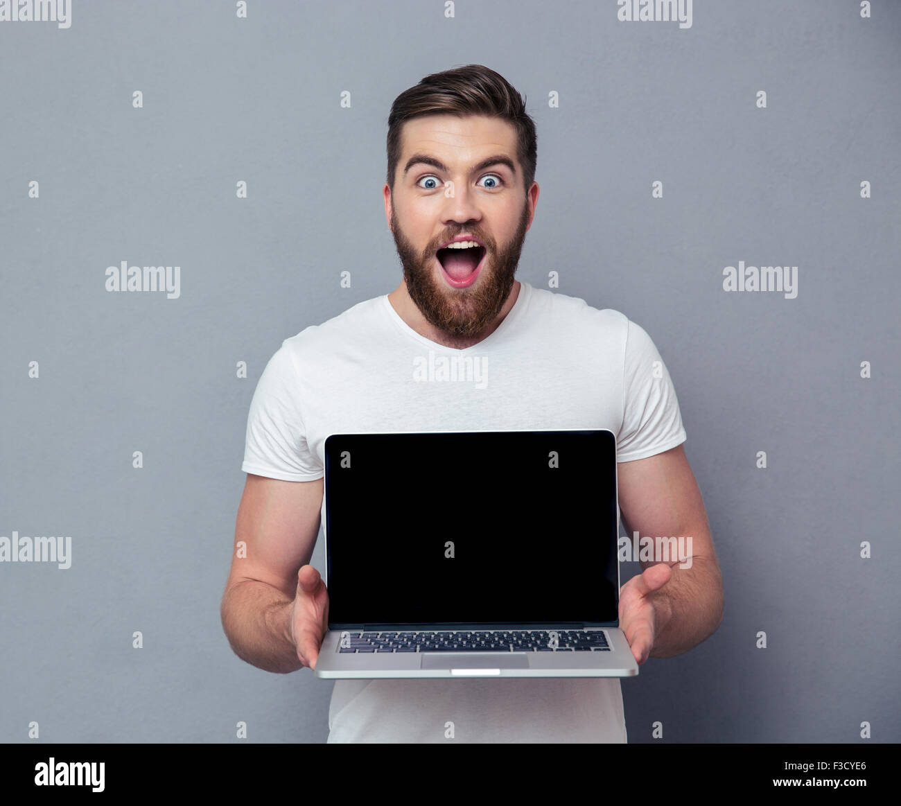 Portrit of a cheerful man showing blank laptop computer screen over ...