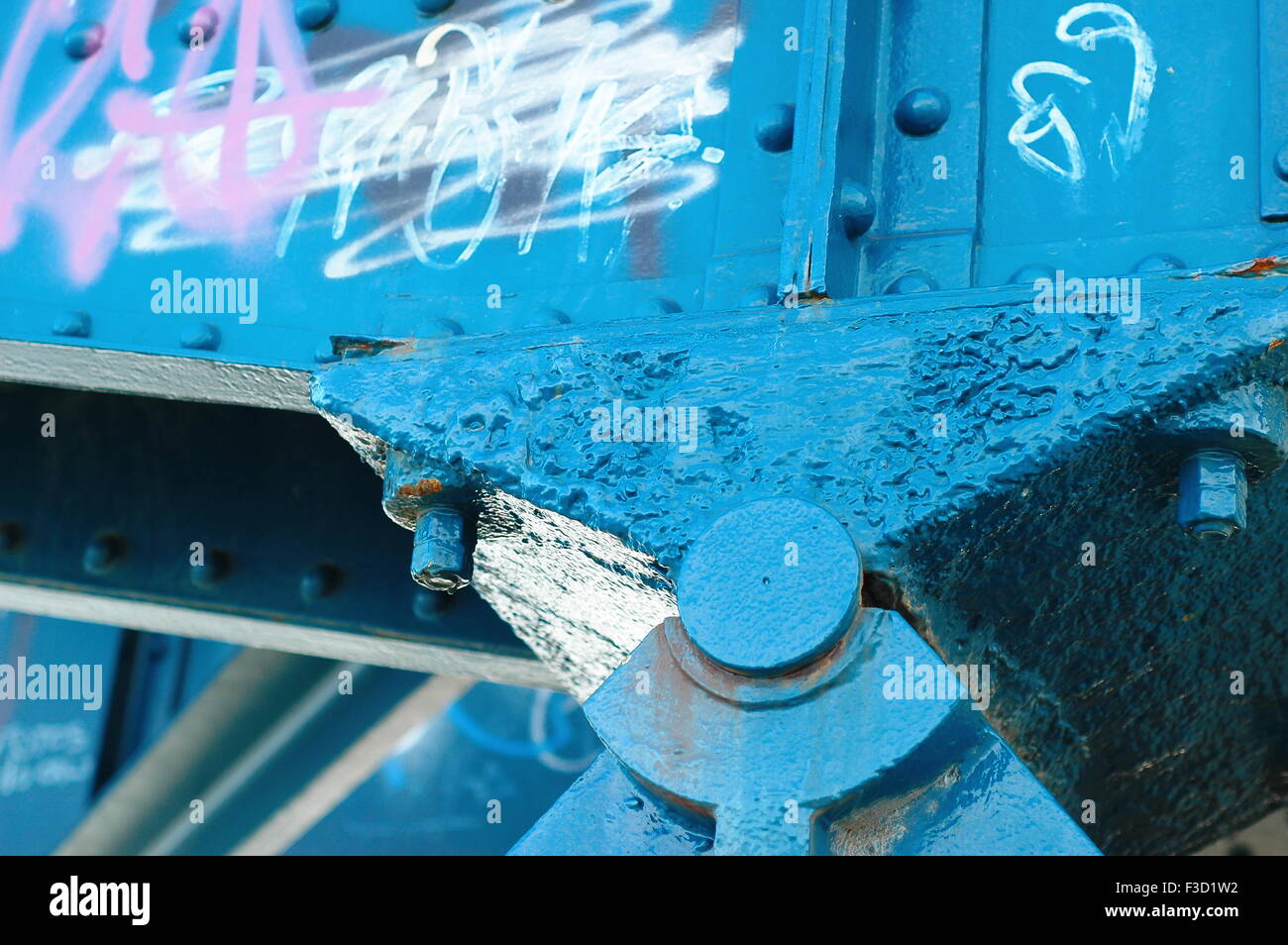 Old textured bridge bearing painted in blue and some grafitties over ...
