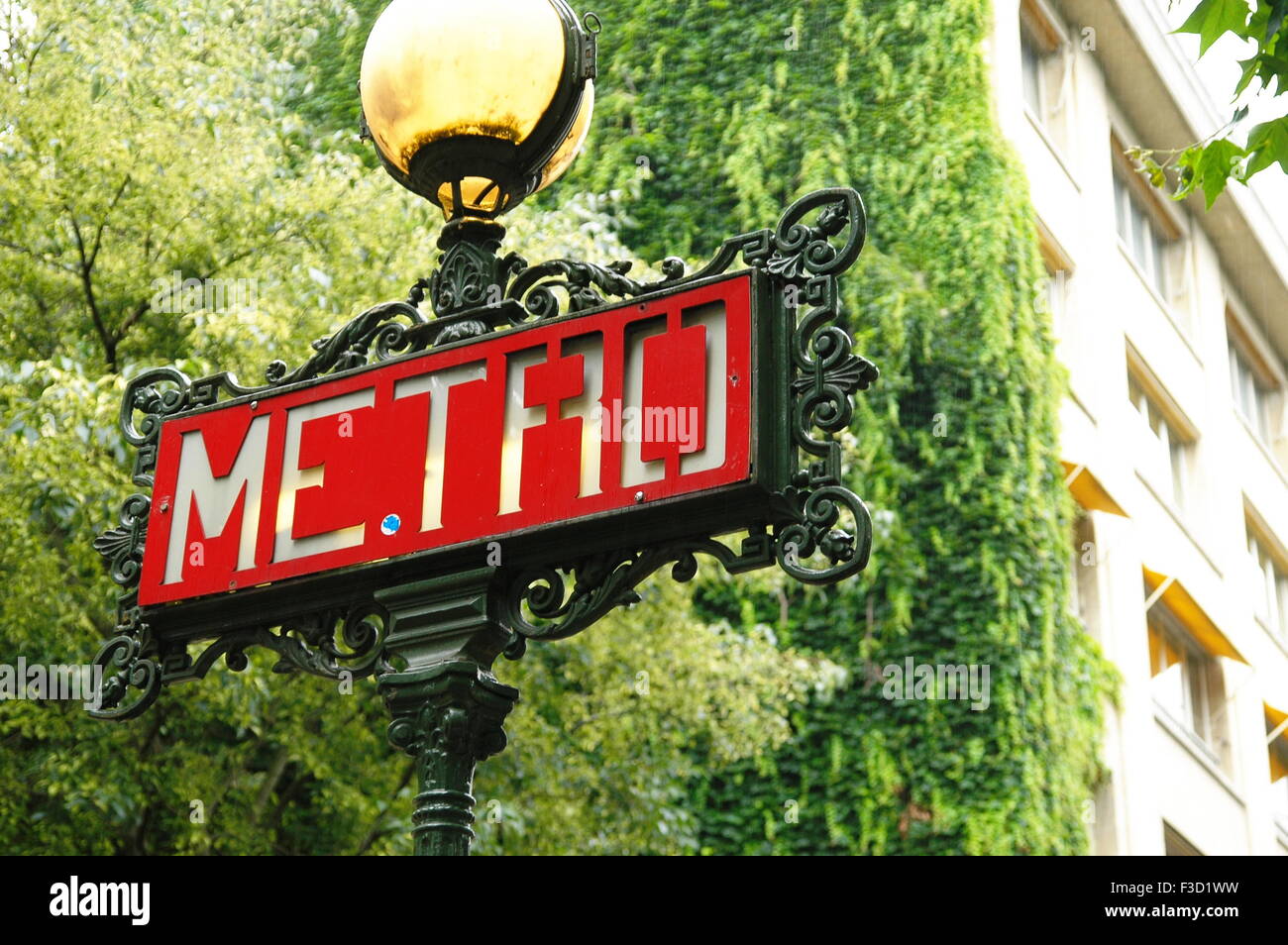 Metro sign in a lamp pole in a street of Paris, over a green background ...