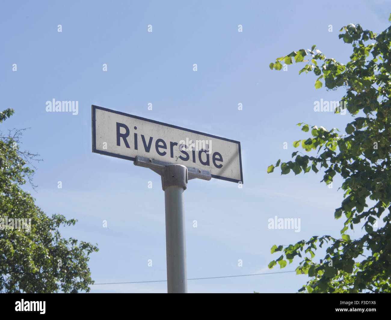 Riverside road sign, signpost with blue sky and green trees in ...