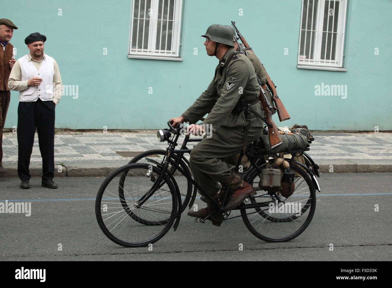 Reenactors uniformed as German Nazi soldiers ride bikes during the ...