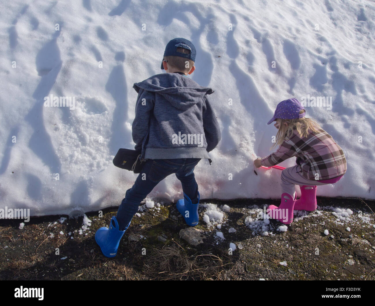 Siblings, boy and girl, playing in a heap of snow, summer in the ...