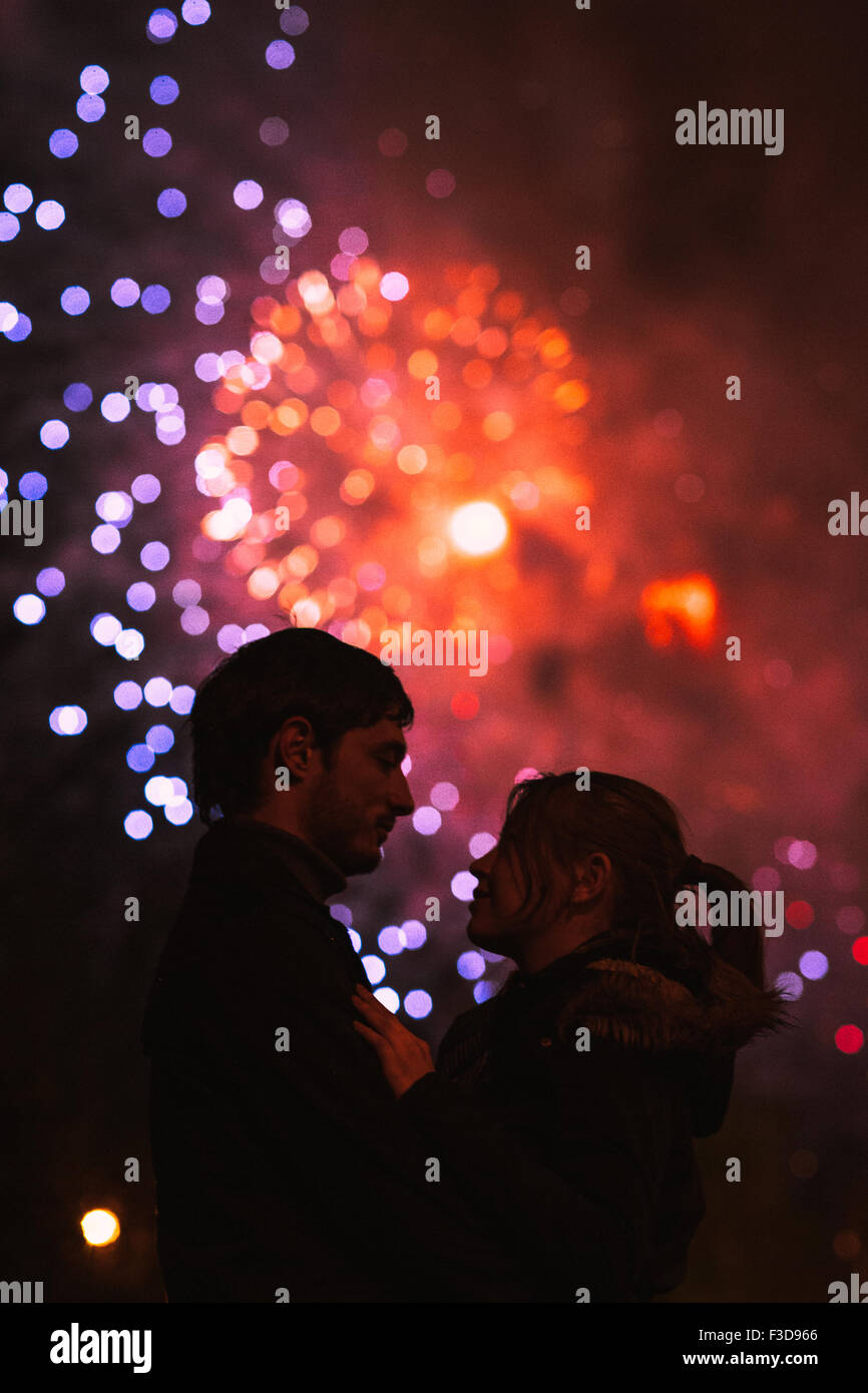 A silhouette of a kissing couple in front of a huge fireworks display ...
