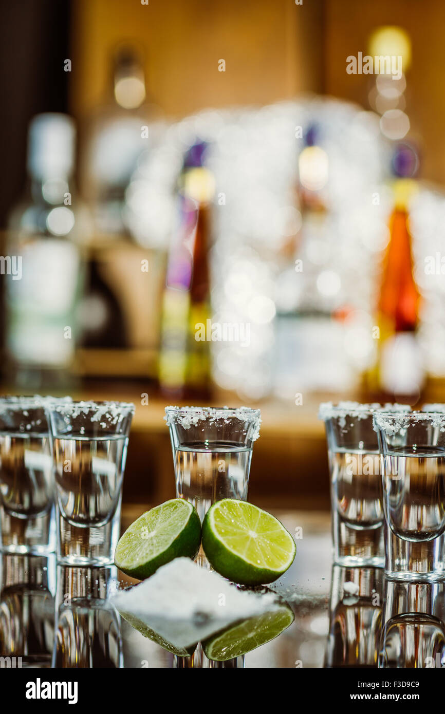 two shots of tequila with lime and salt on a wooden table bar on the ...