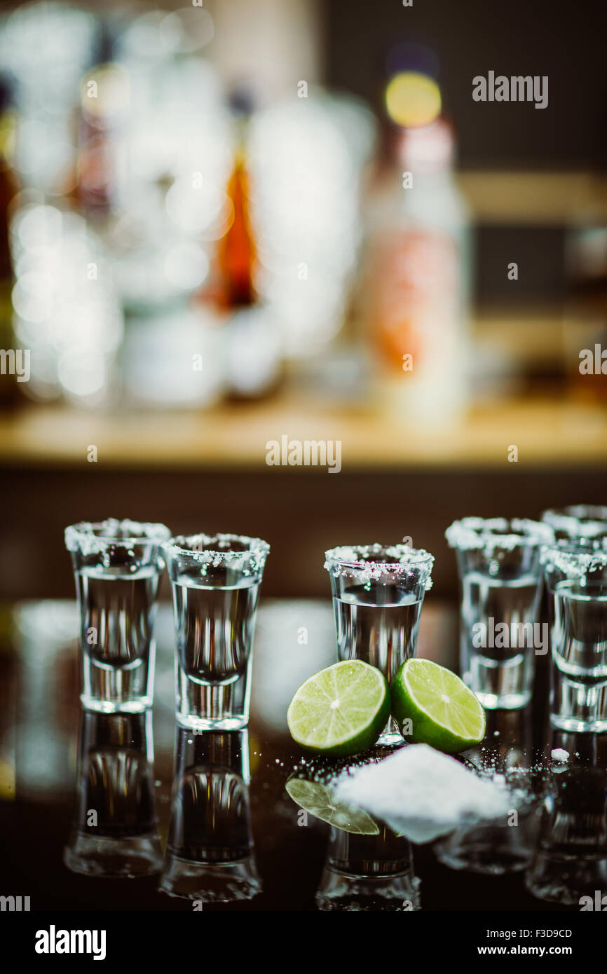 two shots of tequila with lime and salt on a wooden table bar on the ...