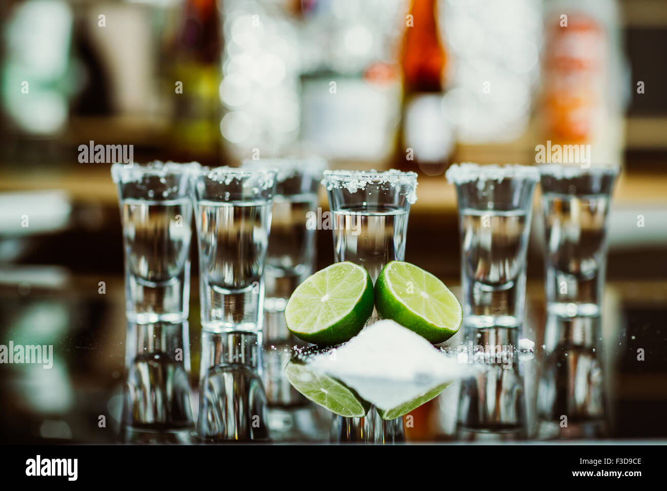 two shots of tequila with lime and salt on a wooden table bar on the ...
