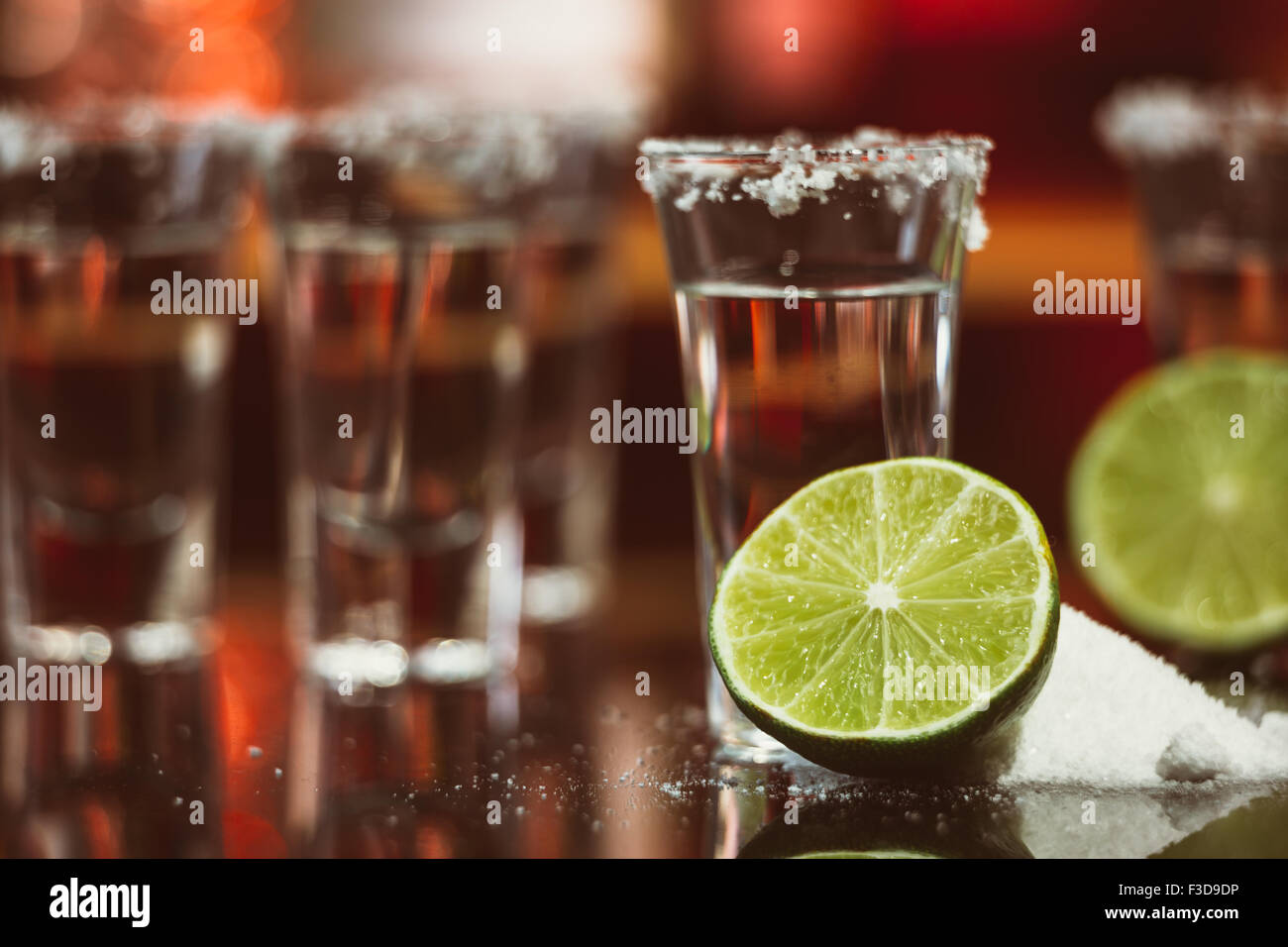 two shots of tequila with lime and salt on a wooden table bar on the ...