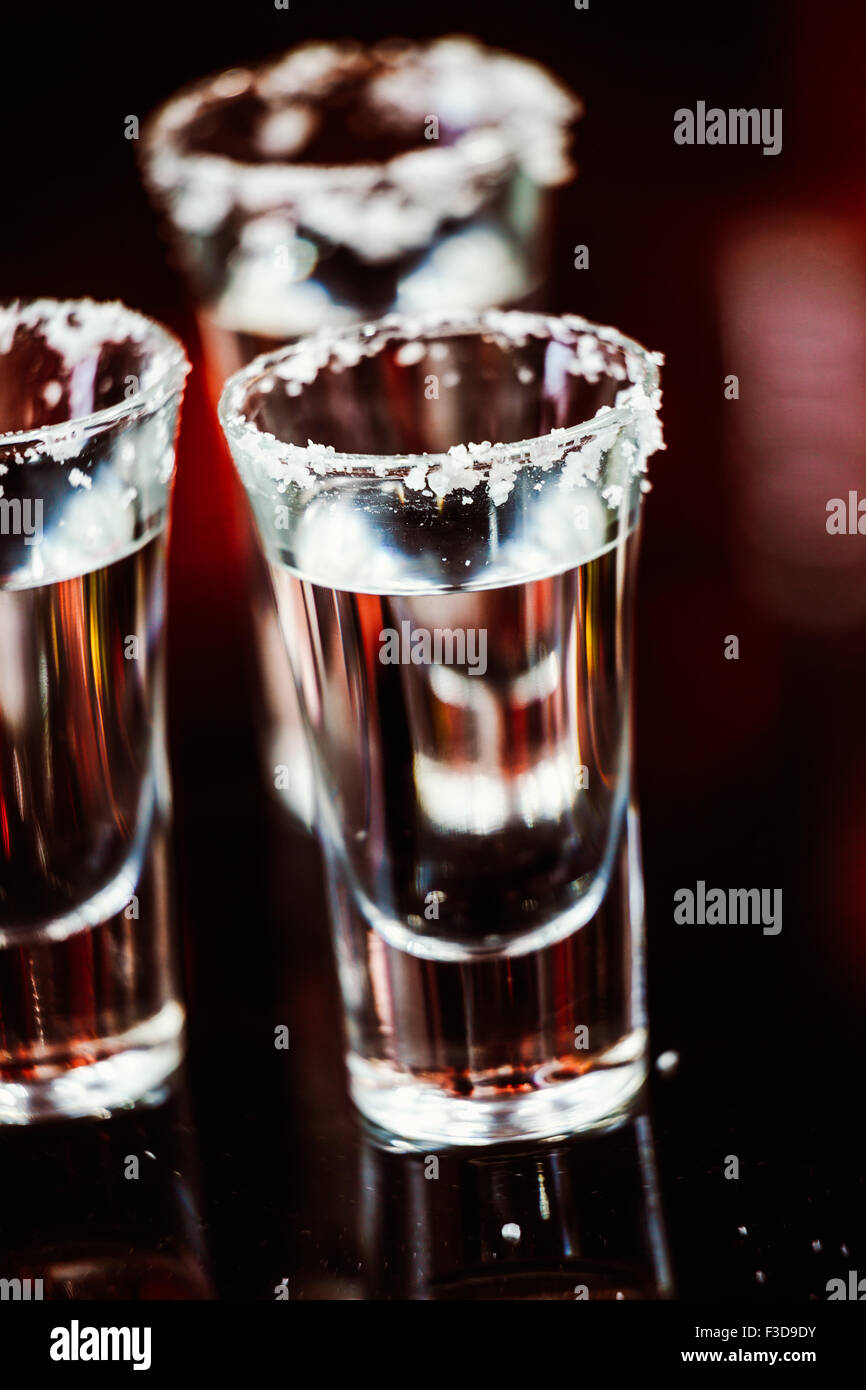 two shots of tequila with lime and salt on a wooden table bar on the ...