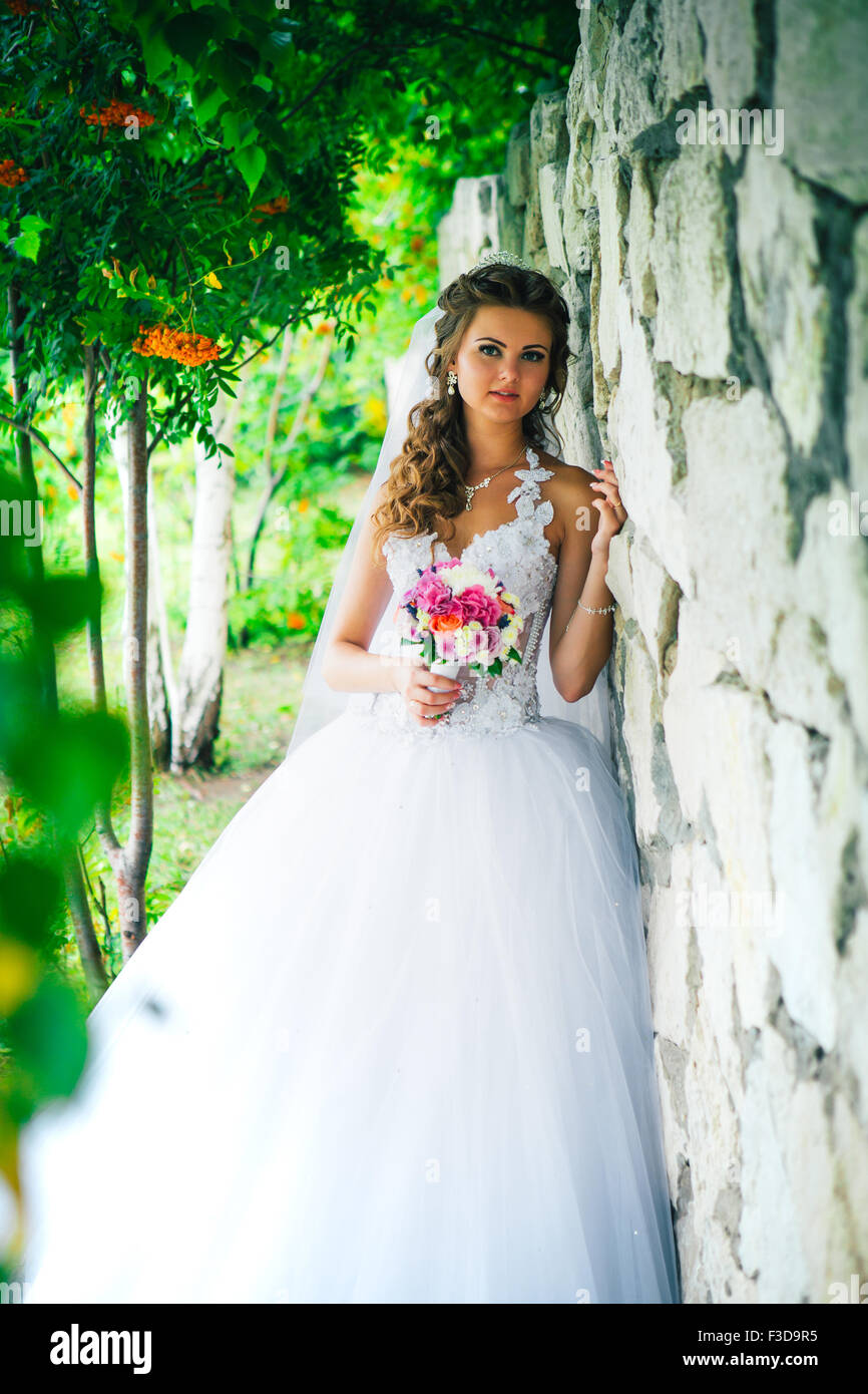 Beautiful young bride standing on a stone wall background Stock Photo ...