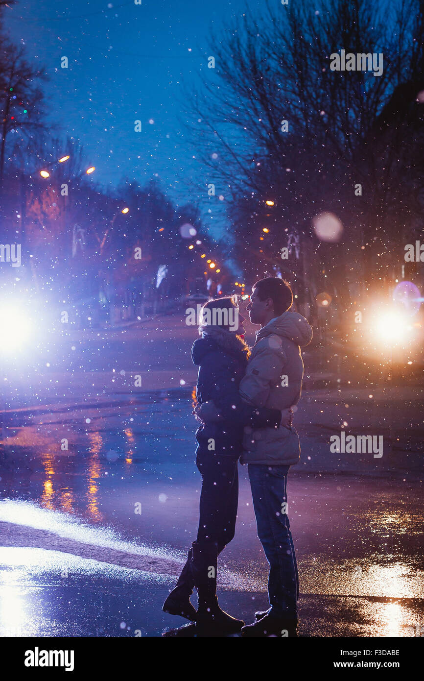 In love couple kissing in the snow at night city street. Filtered with ...