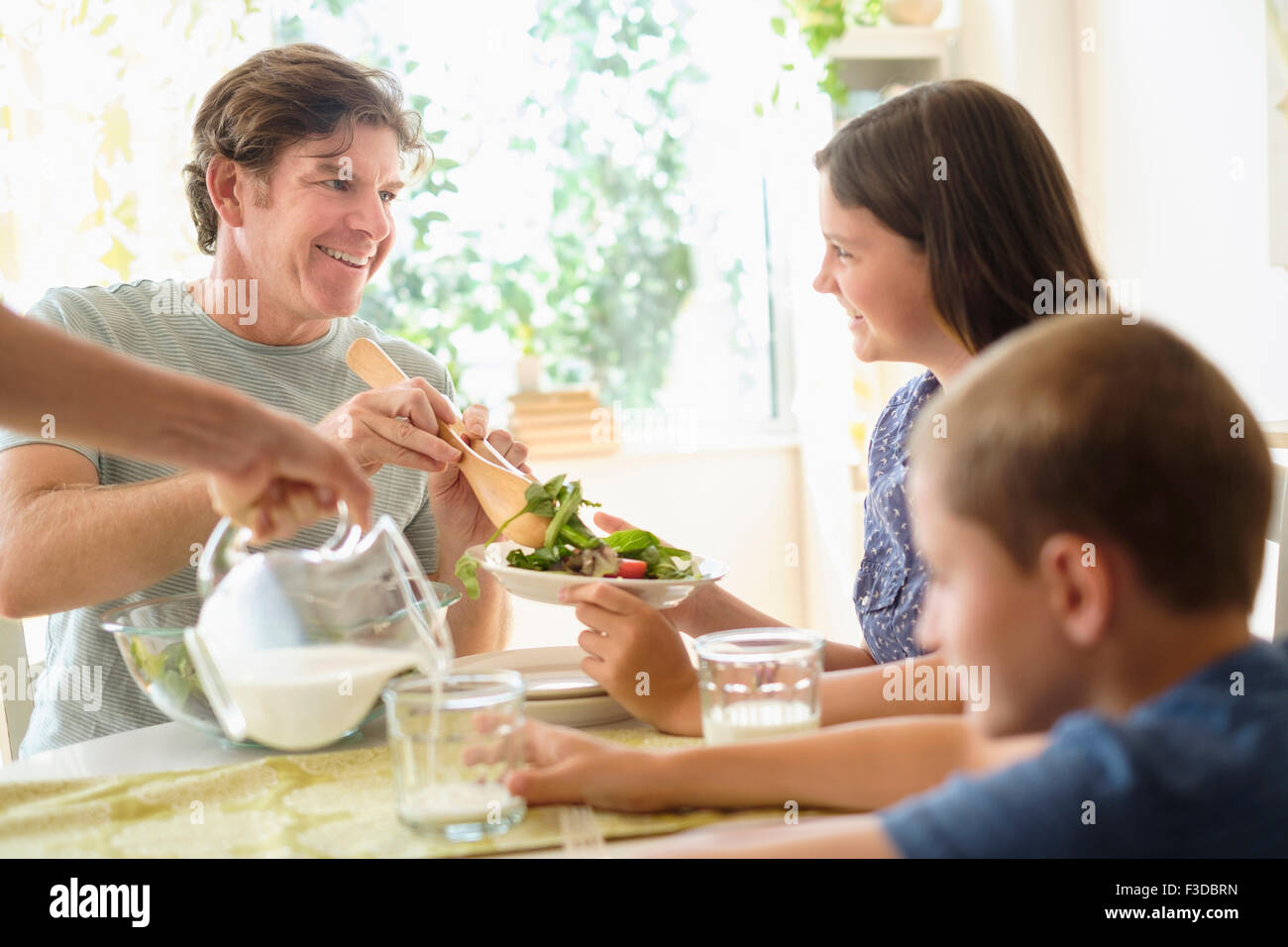 Children (8-9, 10-11) eating salad with parents Stock Photo - Alamy