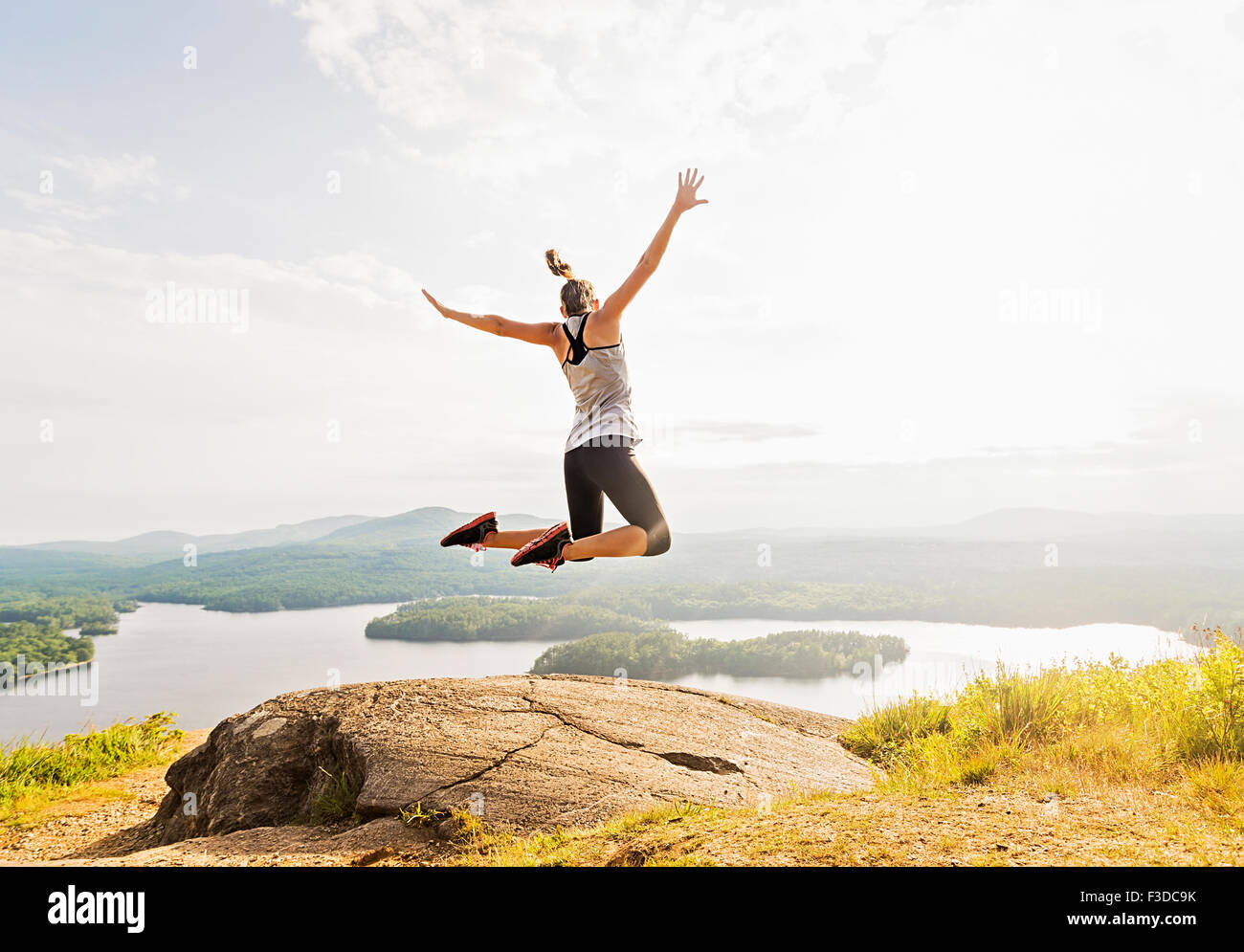 Young woman jumping over mountain top, rear view Stock Photo - Alamy