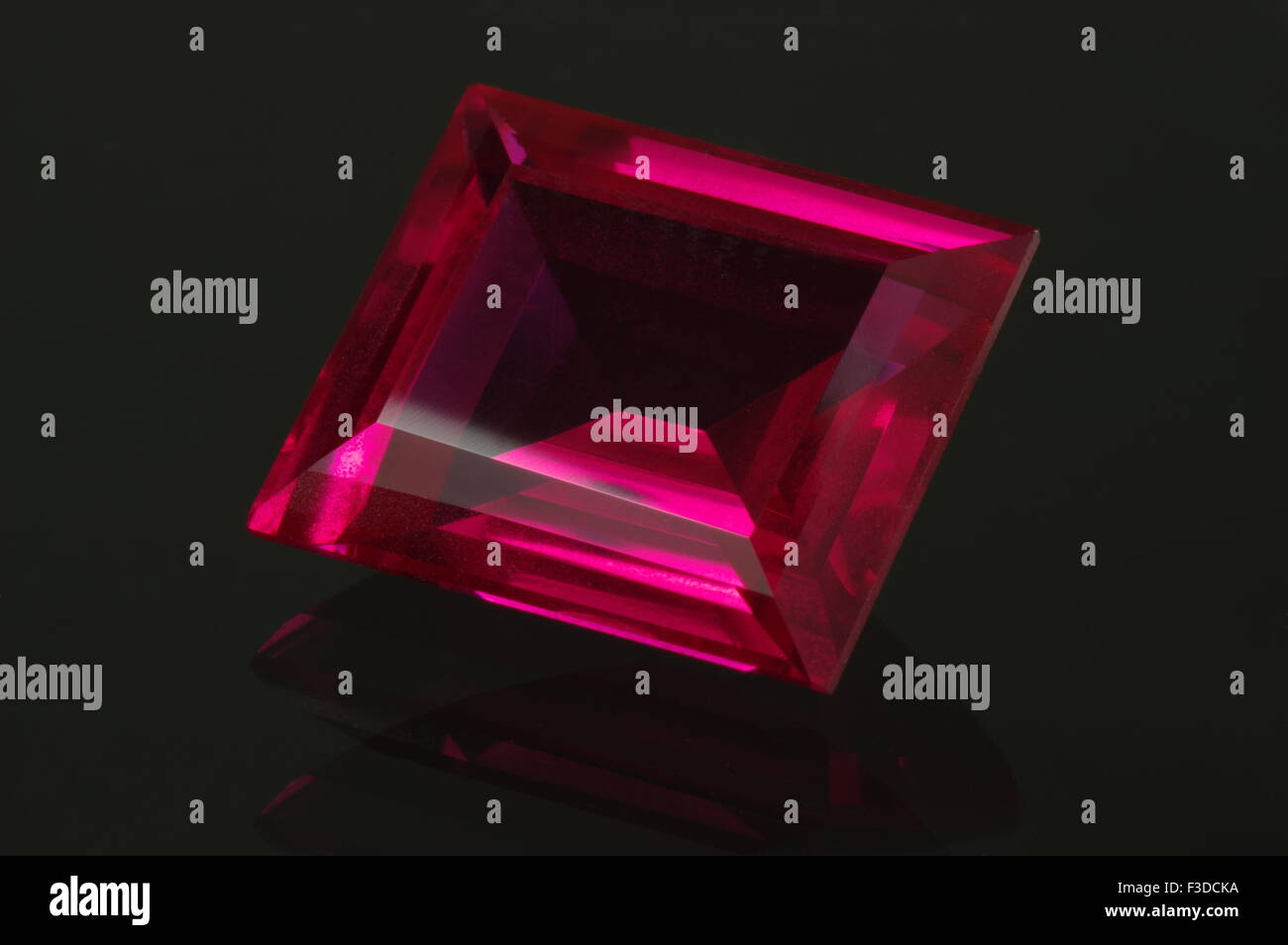 Ruby, grinded synthetic corundum on a black background. Stepped cut ...